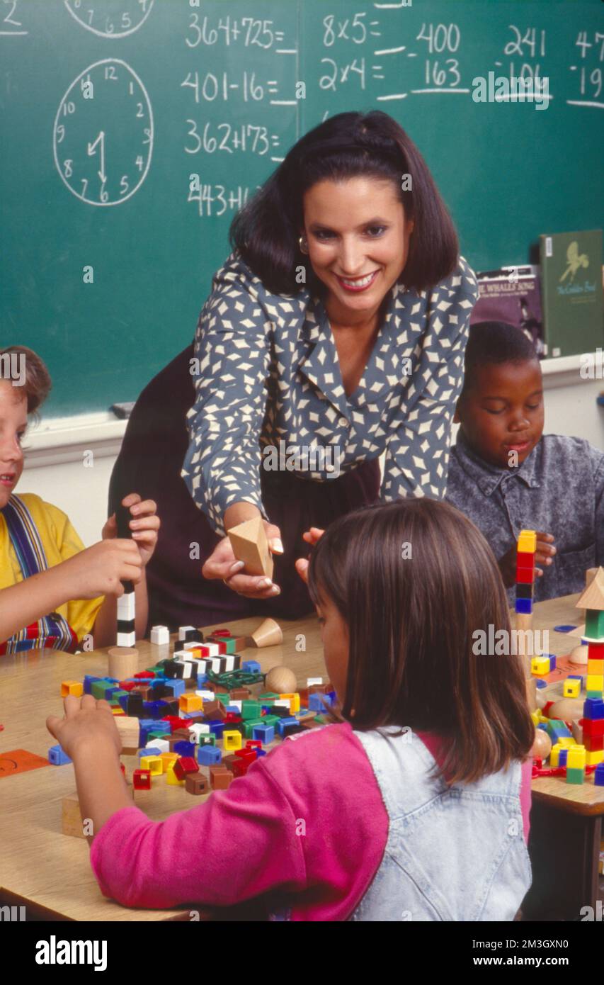 Hispanic elementary school teacher working with students building with ... Hispanic elementary school teacher working with students building with ...