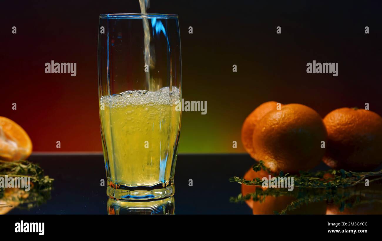 Drink with oranges and bright light on background is poured into glass ...