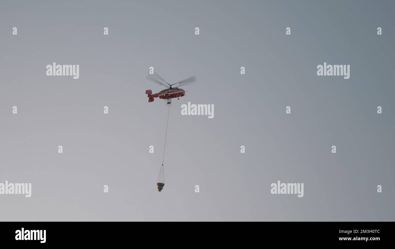 A flying helicopter with cargo . Action . Foggy gray sky with a big red ...