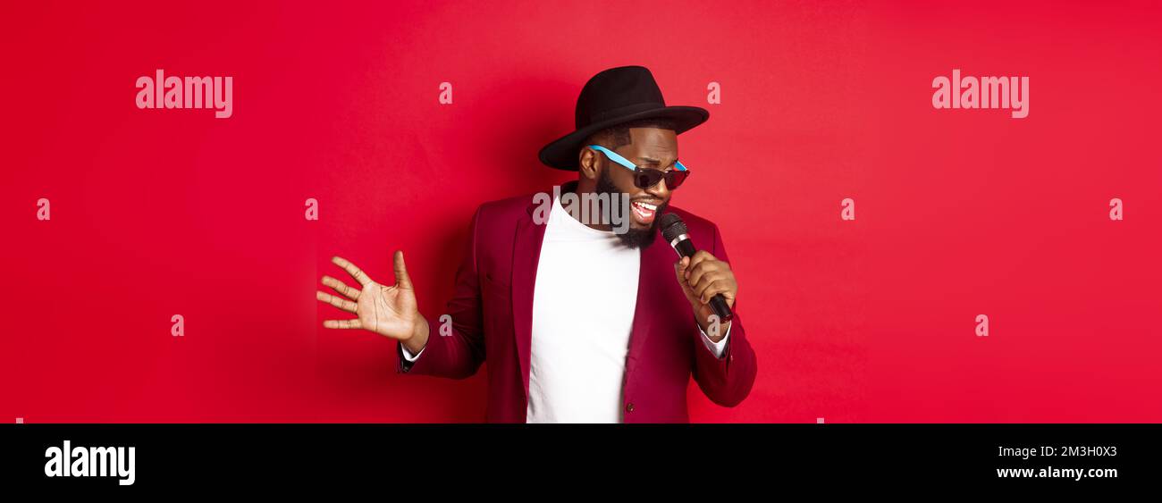Passionate black male singer performing against red background, singing ...