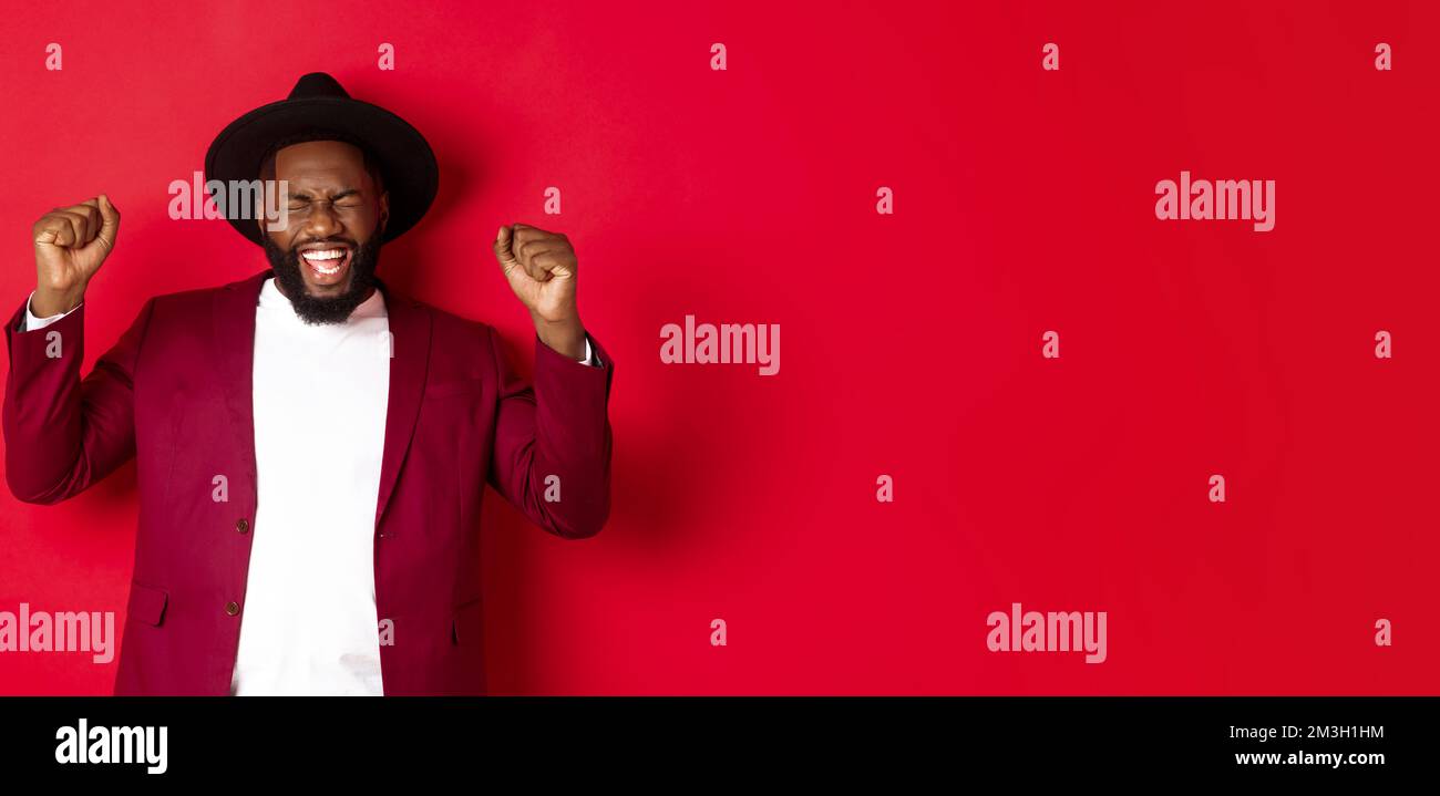 Fashion and party concept. Excited Black man winning prize, shaking ...