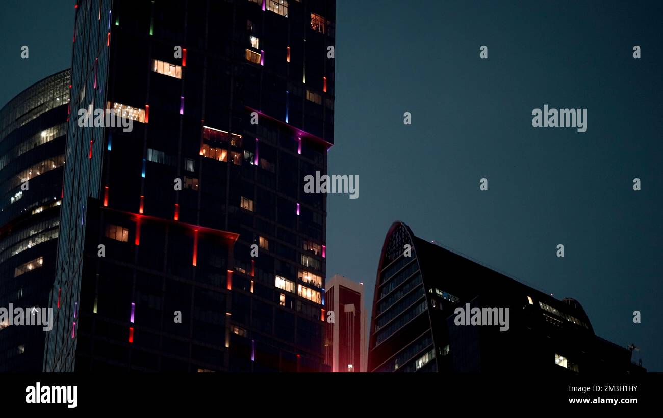 Bottom view of high rise buildings with glowing windows on sunset sky ...