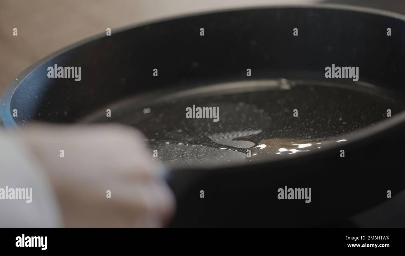 Cooking concept. Action.A large black frying pan on which oil is poured ...