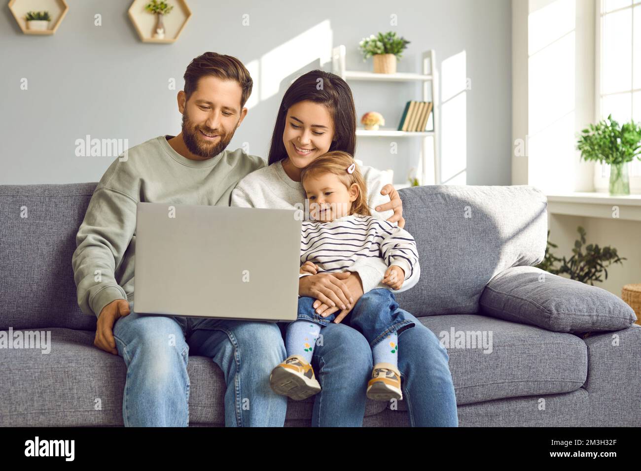 Mom, dad and their little daughter are relaxing at home watching ...