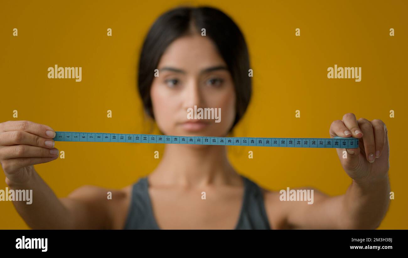 Sad upset worried Indian woman girl in yellow studio with measuring ...