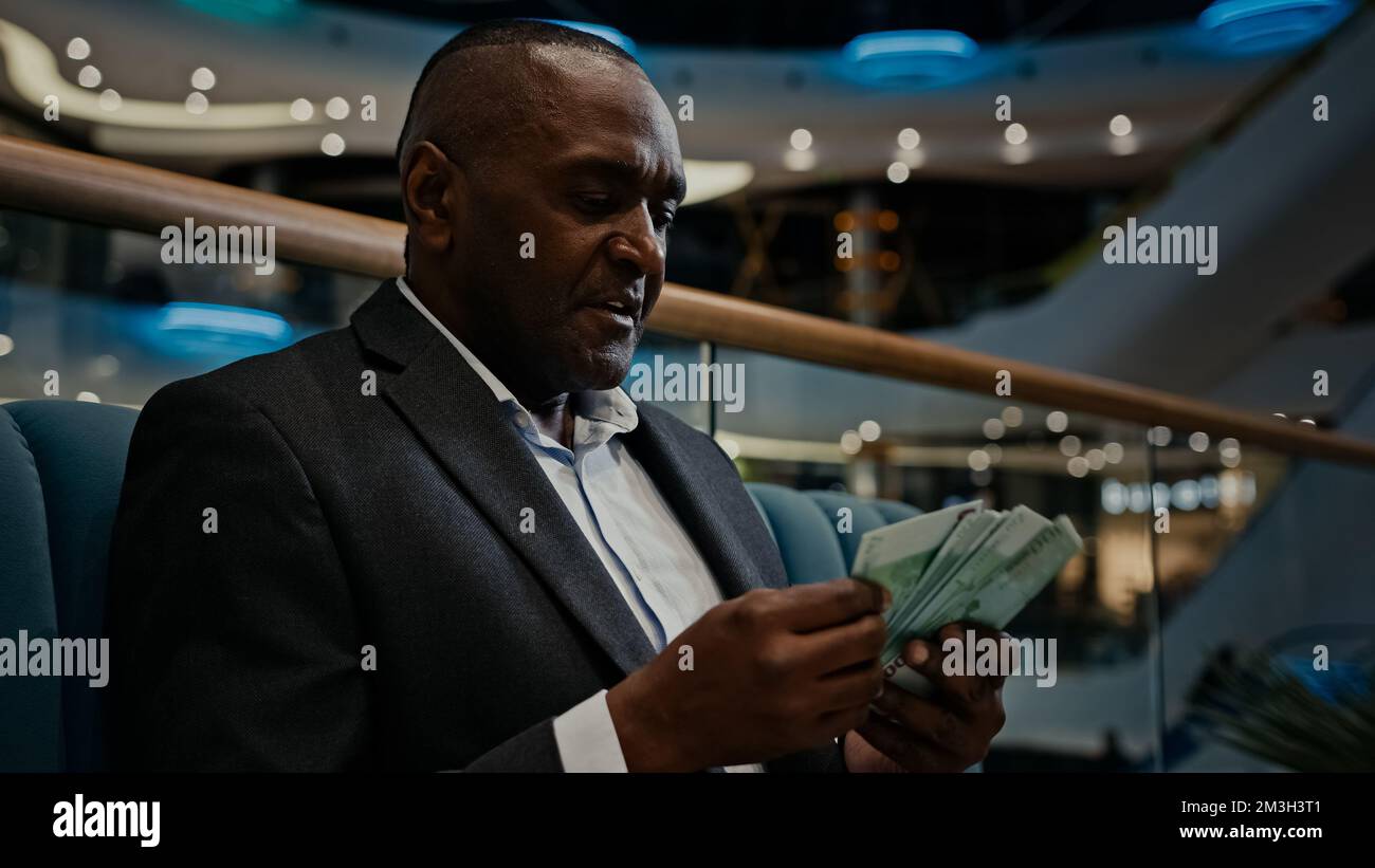 Close up rich 50s African businessman calculate dollars euro indoors ...