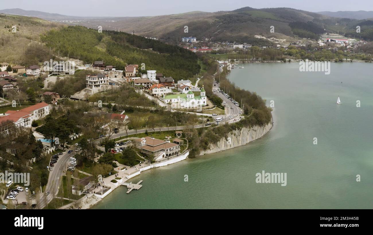 Aerial view of beautiful coastal town along hilly terrain and green sea ...