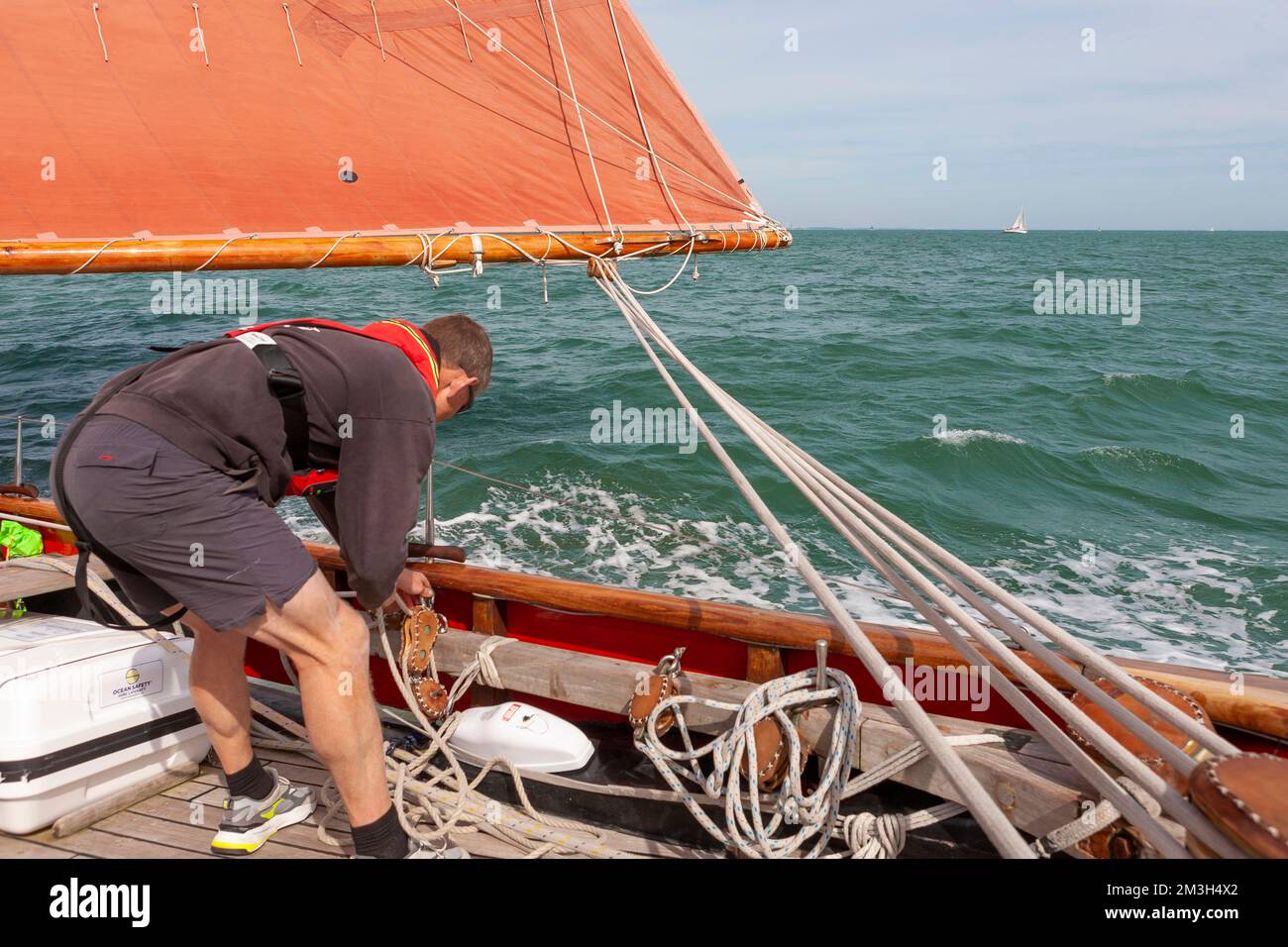 Crew member working aboard the traditional gaff cutter "Jolie Brise ...