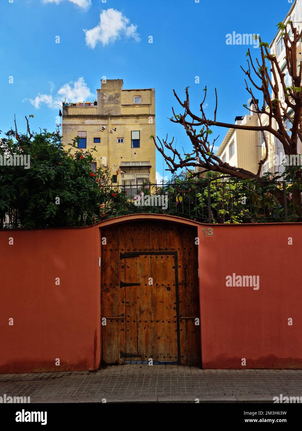 Red wall and door. Entrance of a house with garden. Gracia quarter ...