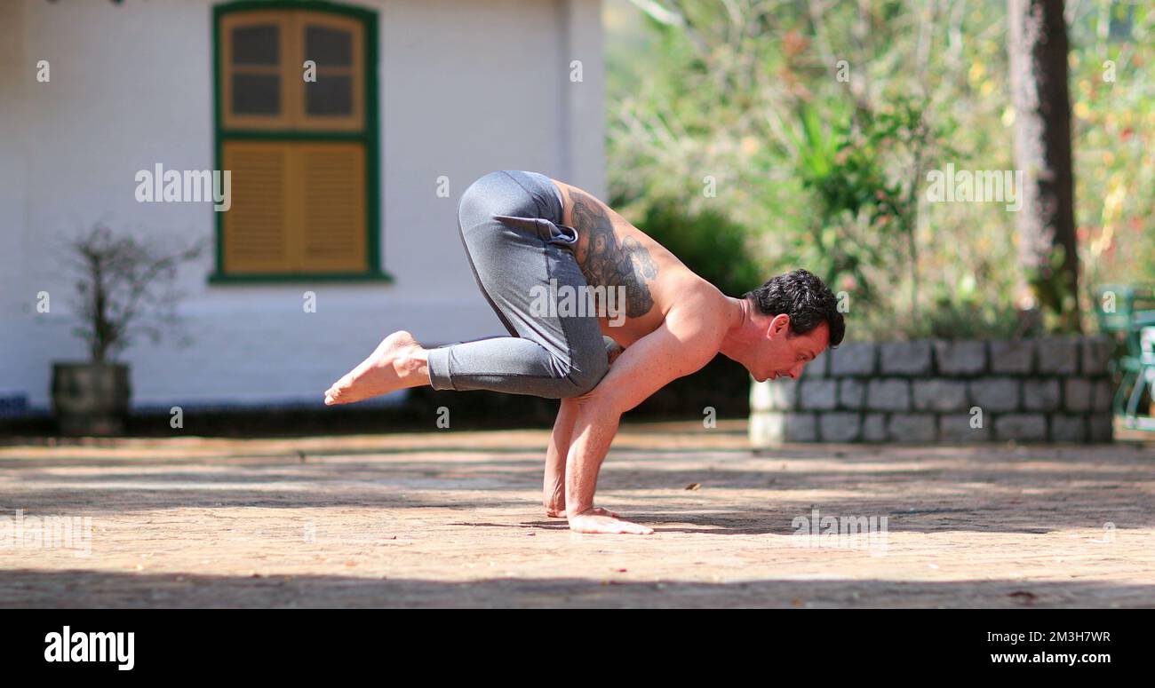 Man training Bakasana Yoga asana outdoors Stock Photo - Alamy