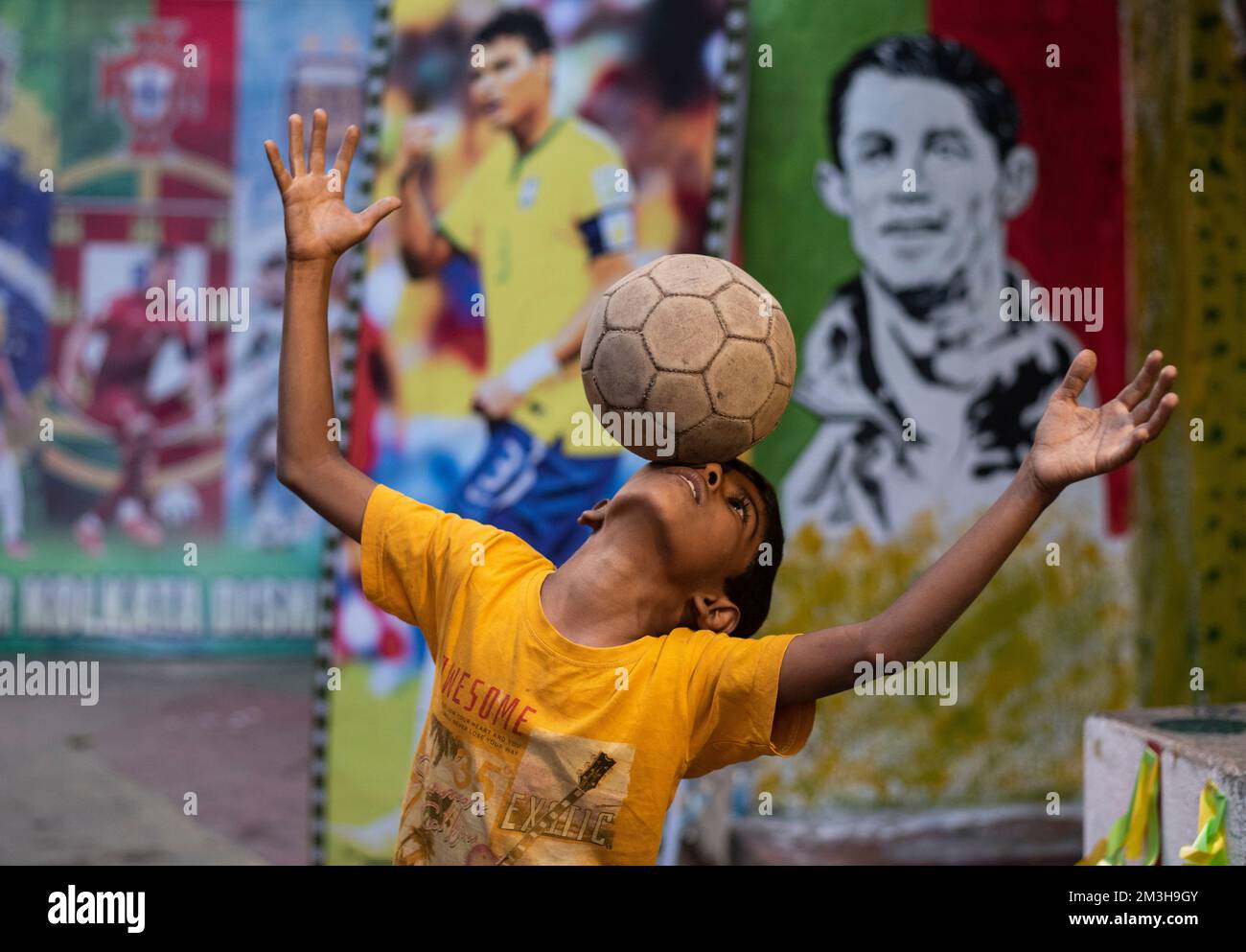 KOLKATA, INDIA - DECEMBER 12: A boy playing football next to decked up ...