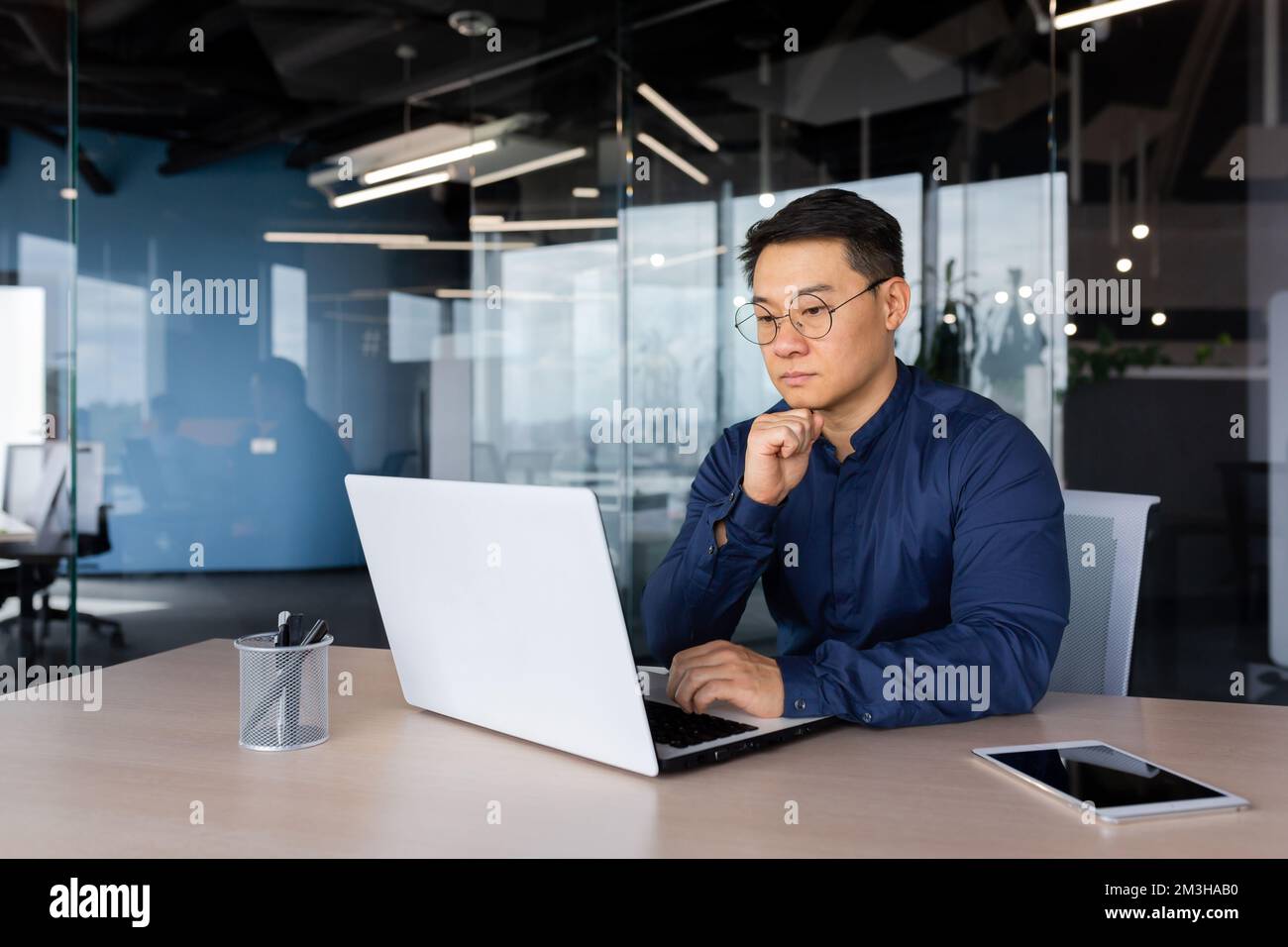 Serious thinking asian businessman working inside modern office, mature ...