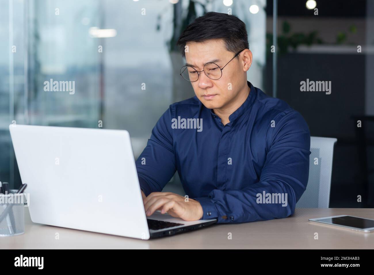 Serious thinking asian businessman working inside modern office, mature ...