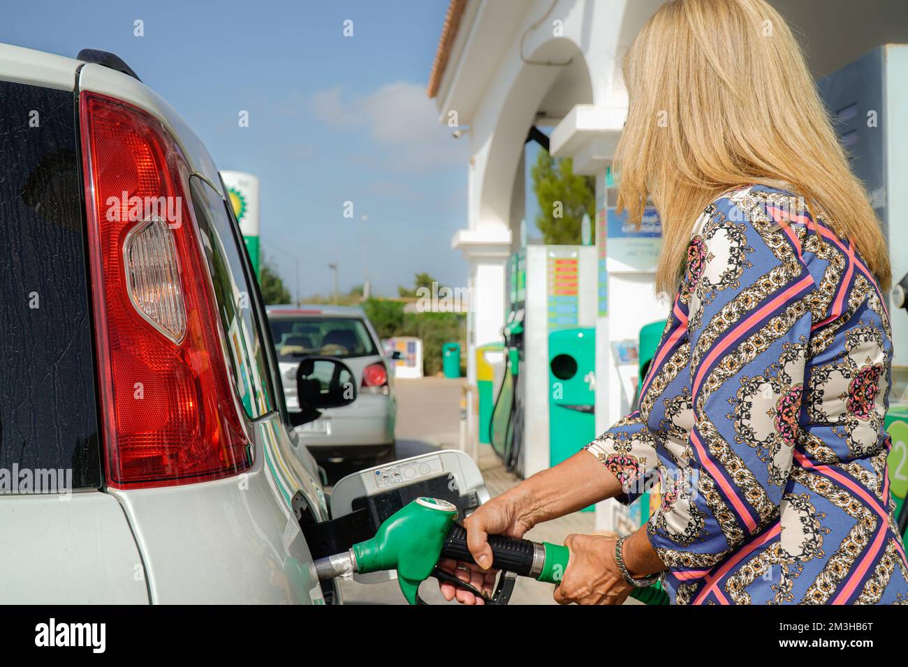 female refueling her vehicle at a gas station. diesel price. Women ...