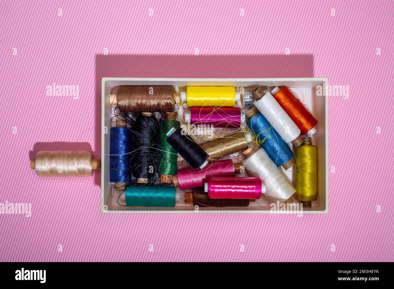 A box with multi colored coins of different threads on a colored ...