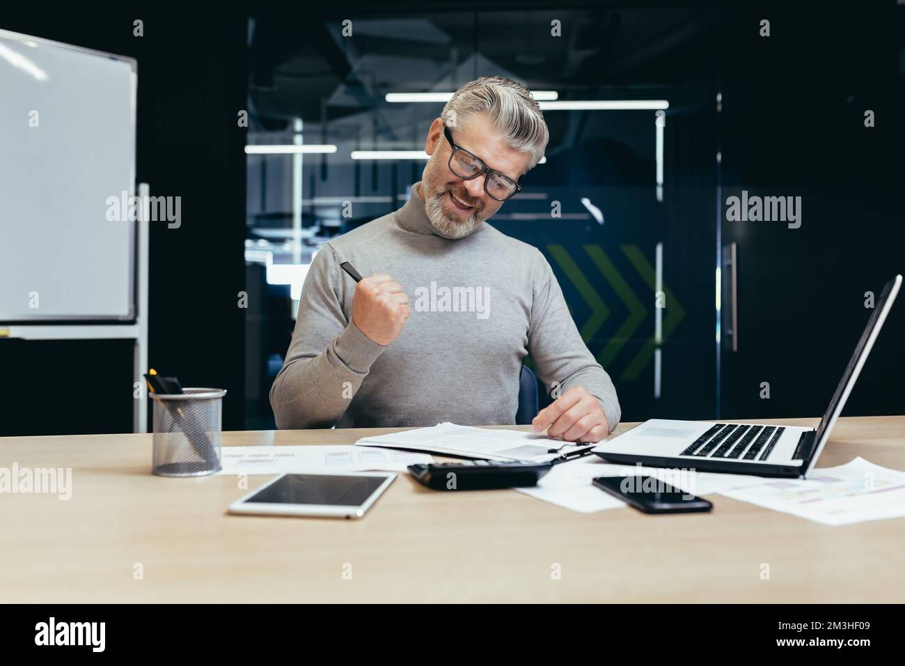 Happy senior business man sitting in the office at the table and ...