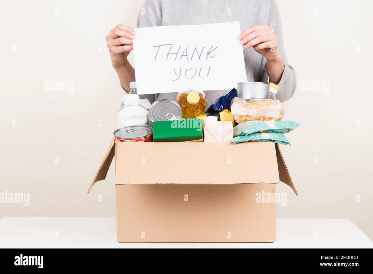 Female hands holding cardboard box with grocery products and card with ...