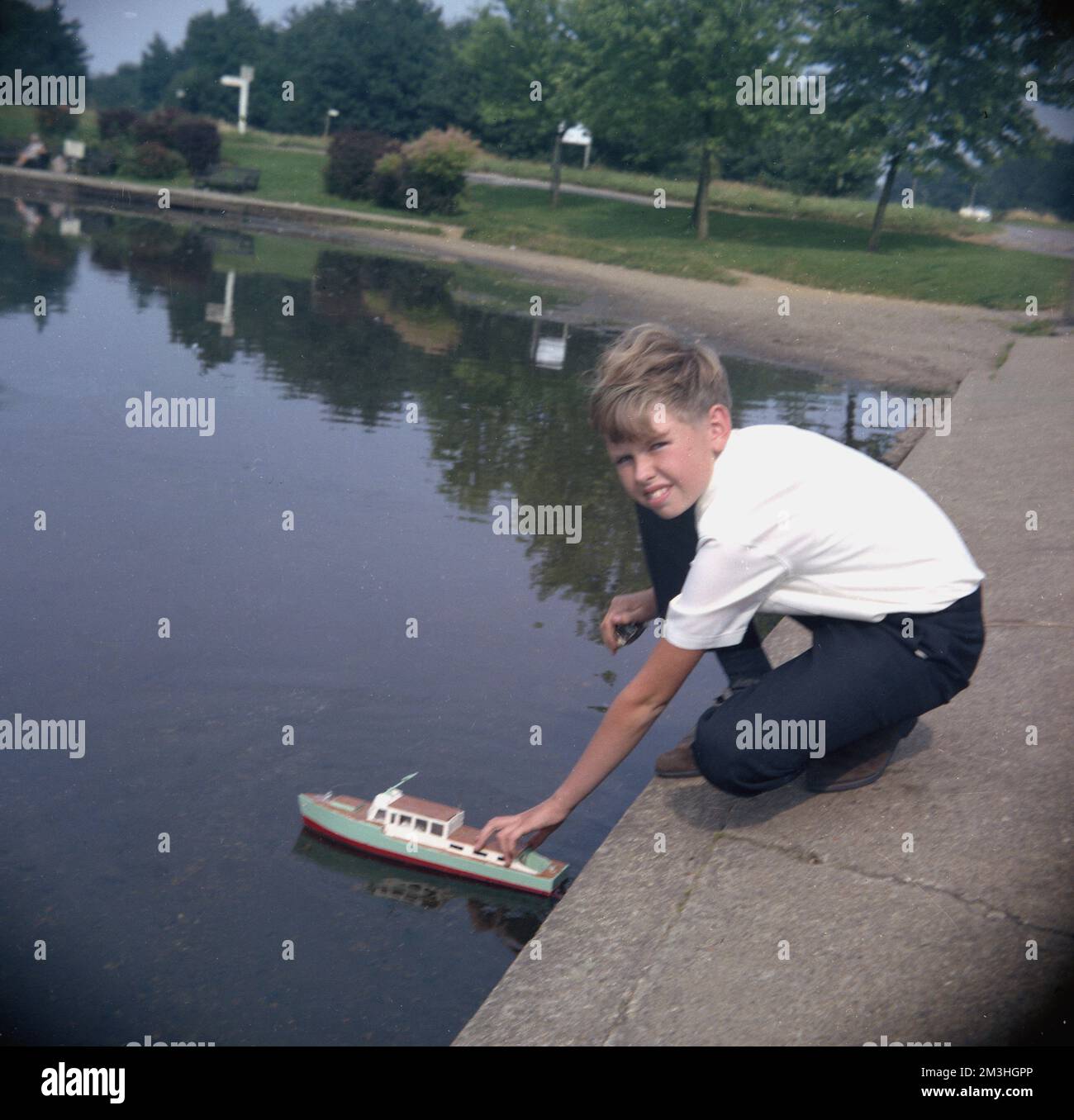 Late '60s, historical, a boy playing with his wooden model boat on the ...