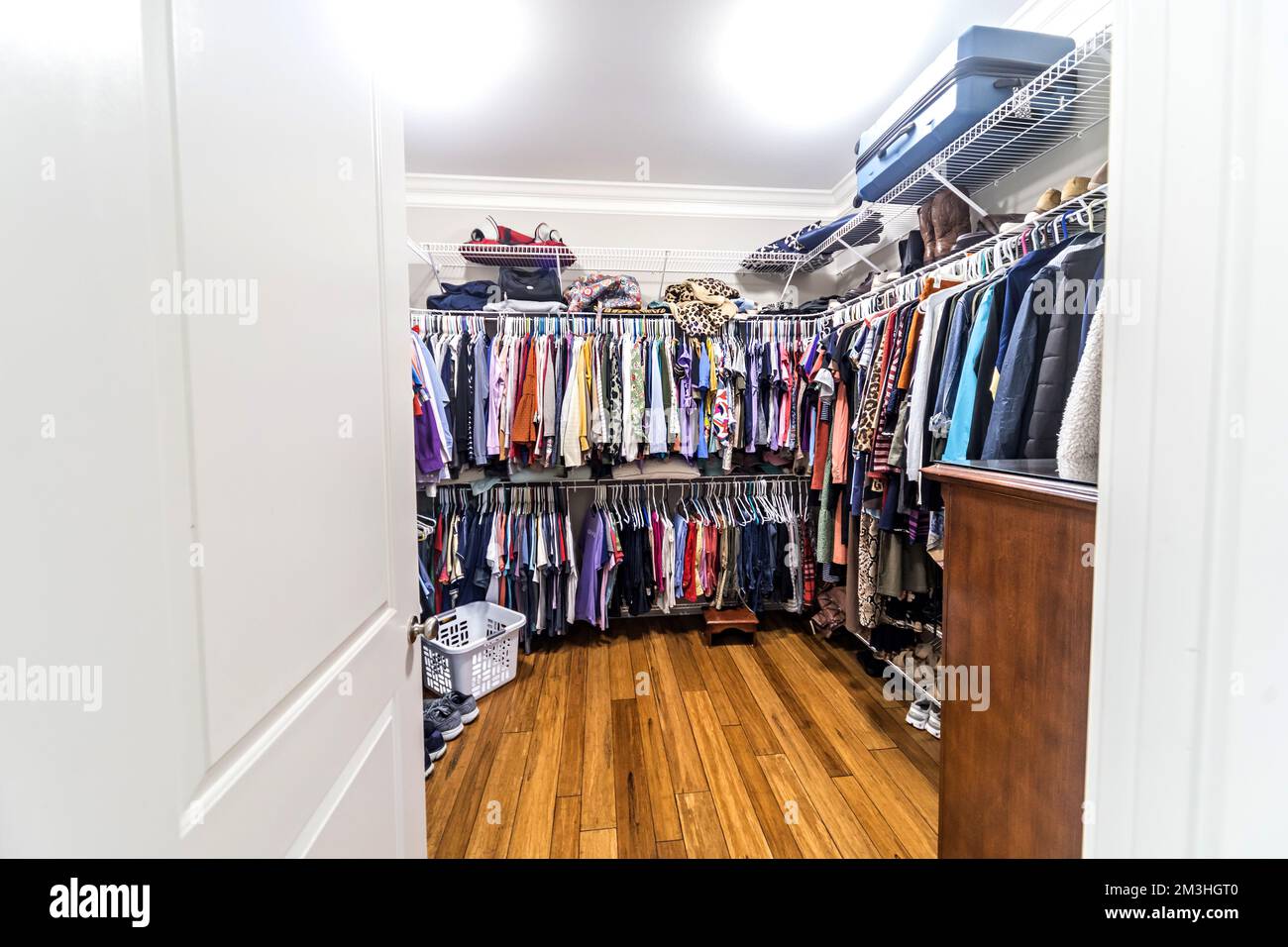 A full and stuffed master bedroom closet in a new construction home with wood floors Stock Photo ...