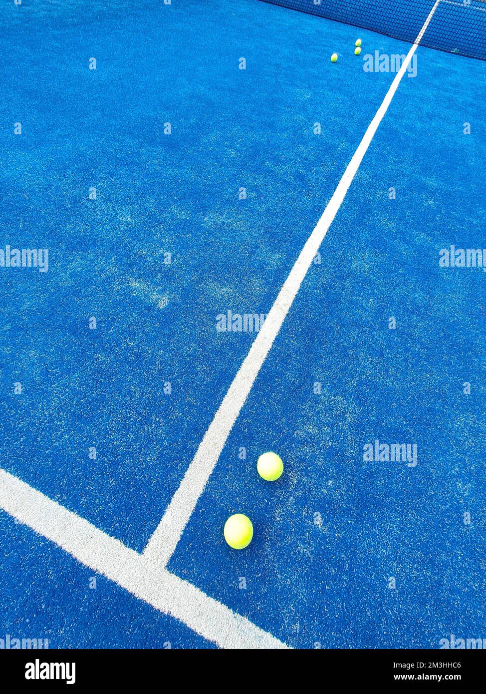 A vertical top view of two green balls on a blue artificial grass ...