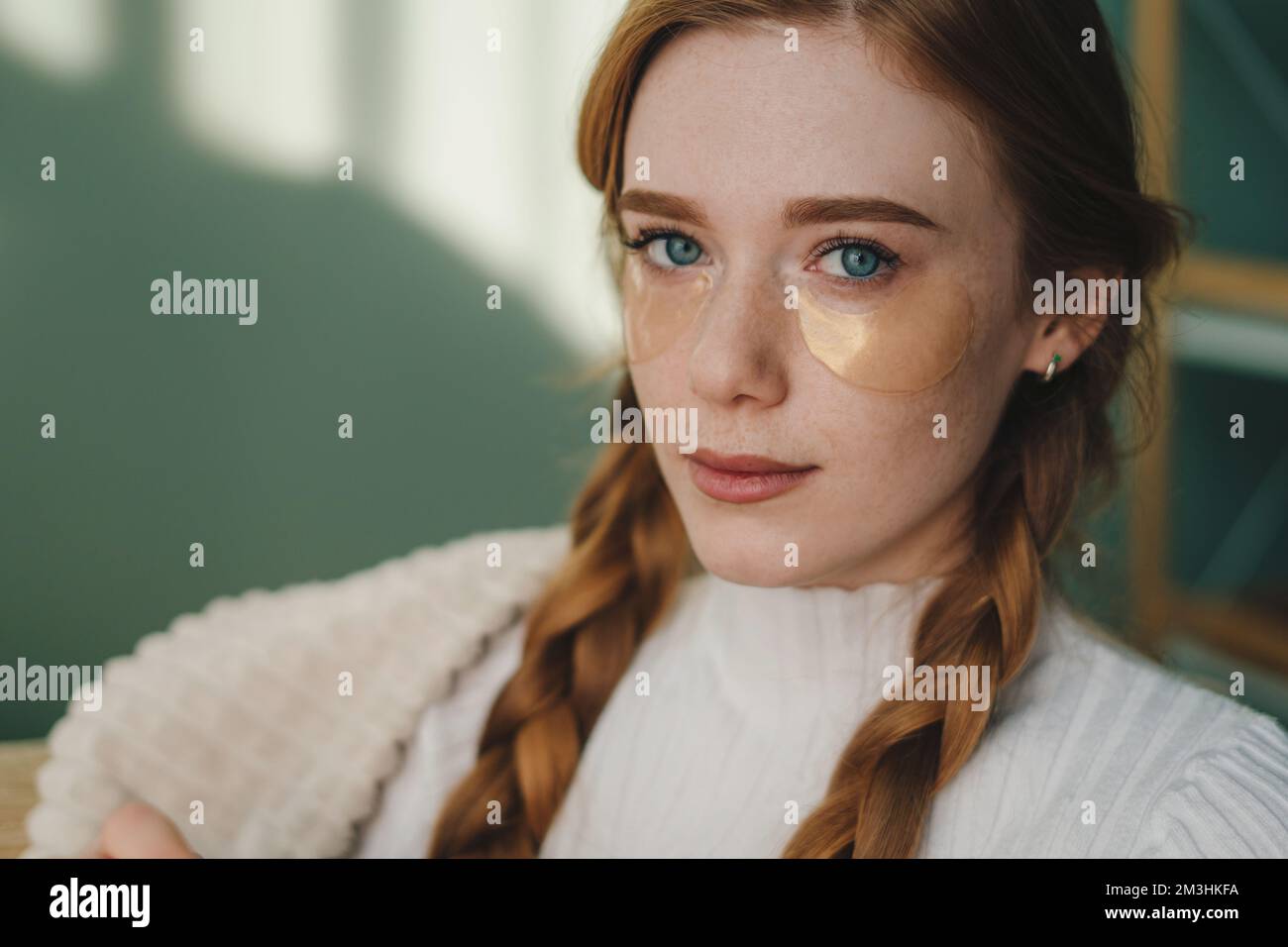 Freckled girl with eye-patches under eyes looking at camera with blue ...