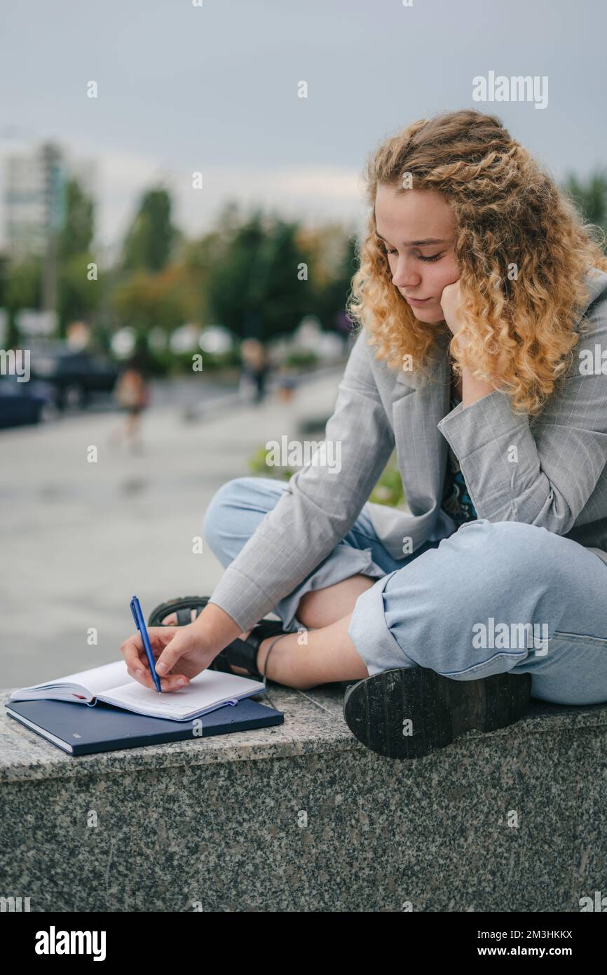 Photo of a thoughtful young beautiful curly student girl sitting ...