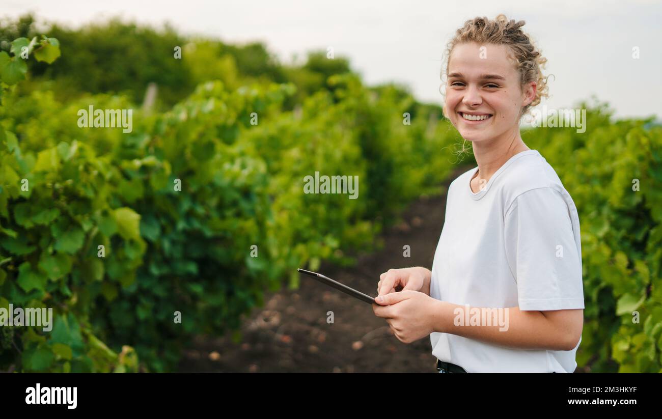 Farmer woman recording the growing of grapes in her vine fields on a ...