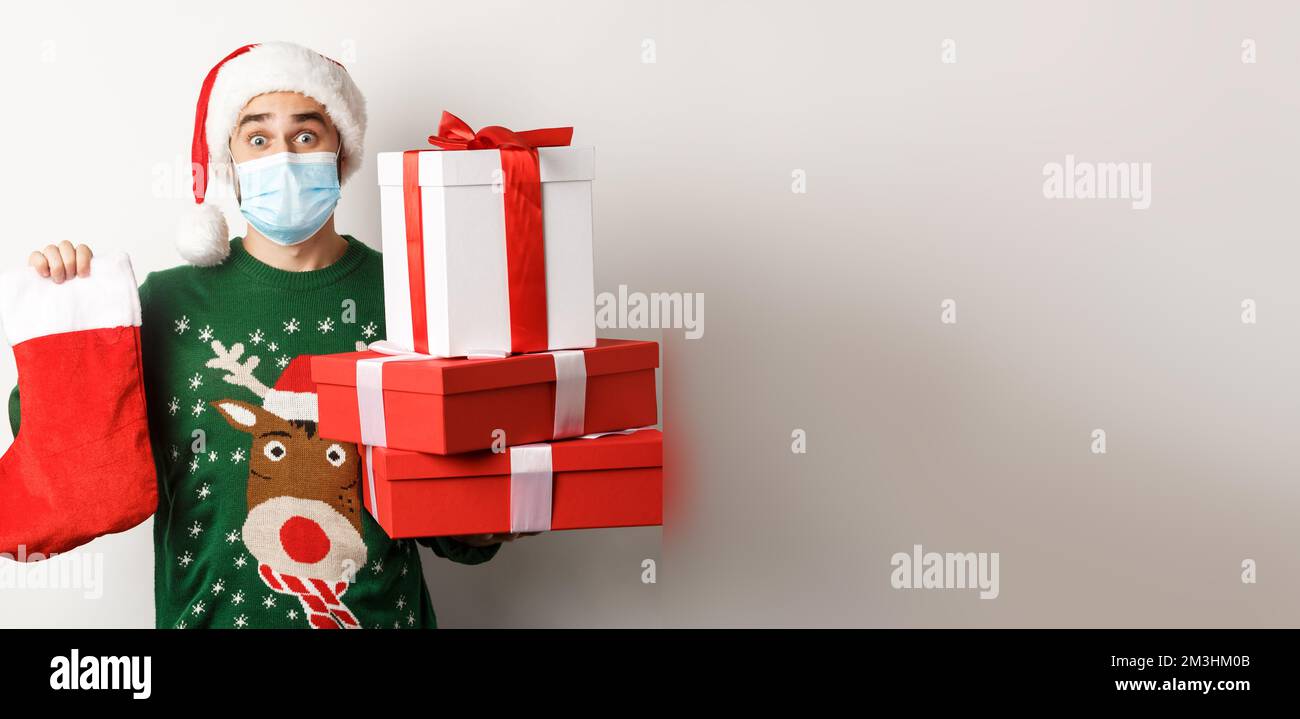 Winter holidays and xmas concept. Happy man in face mask and santa hat ...