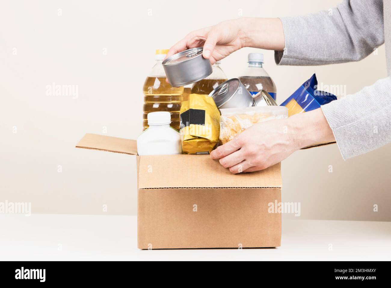 Woman volunteer hands collecting food into donation box full of grocery ...