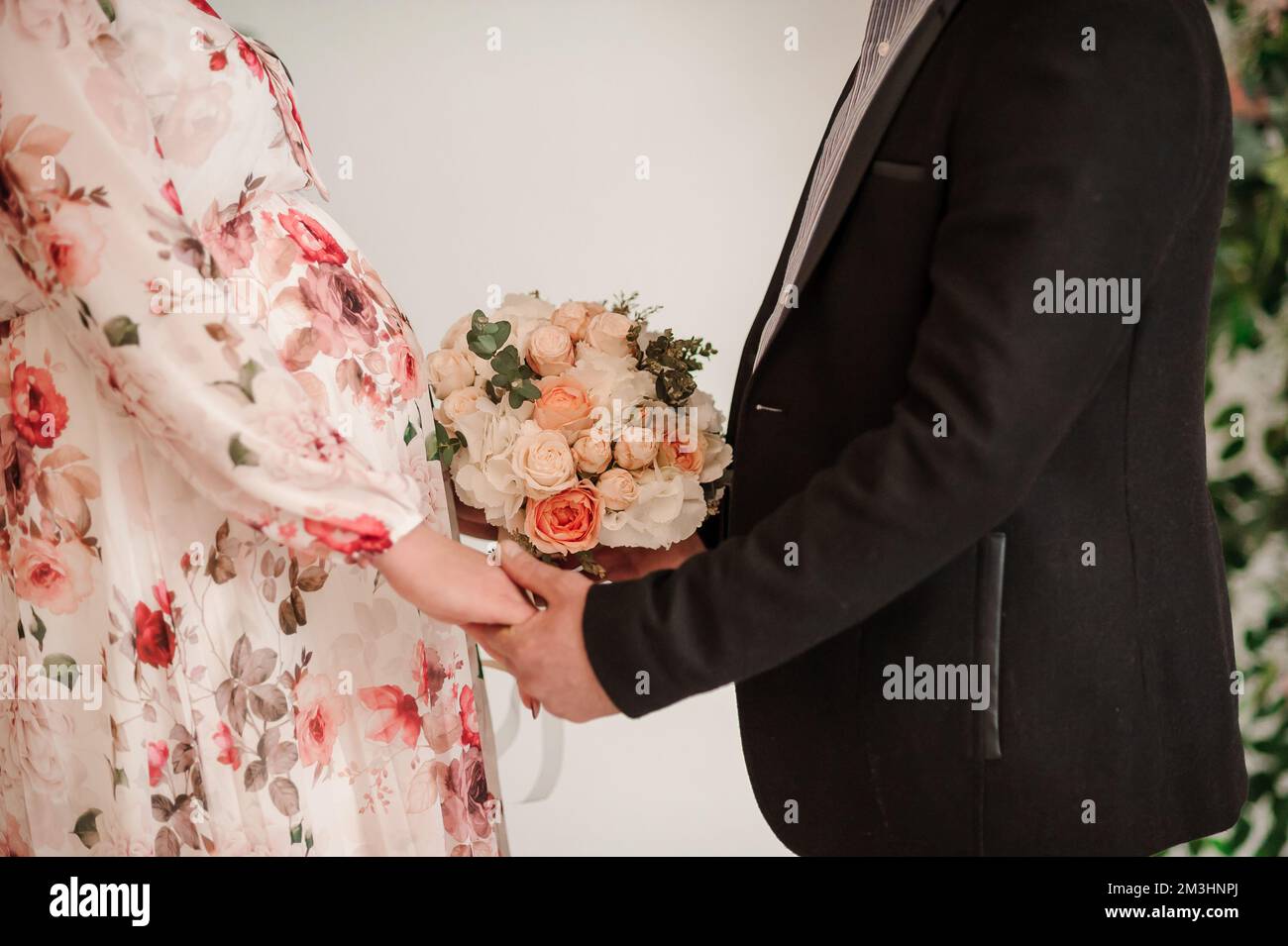The groom holds the bride's hand, in the background a wedding bouquet ...