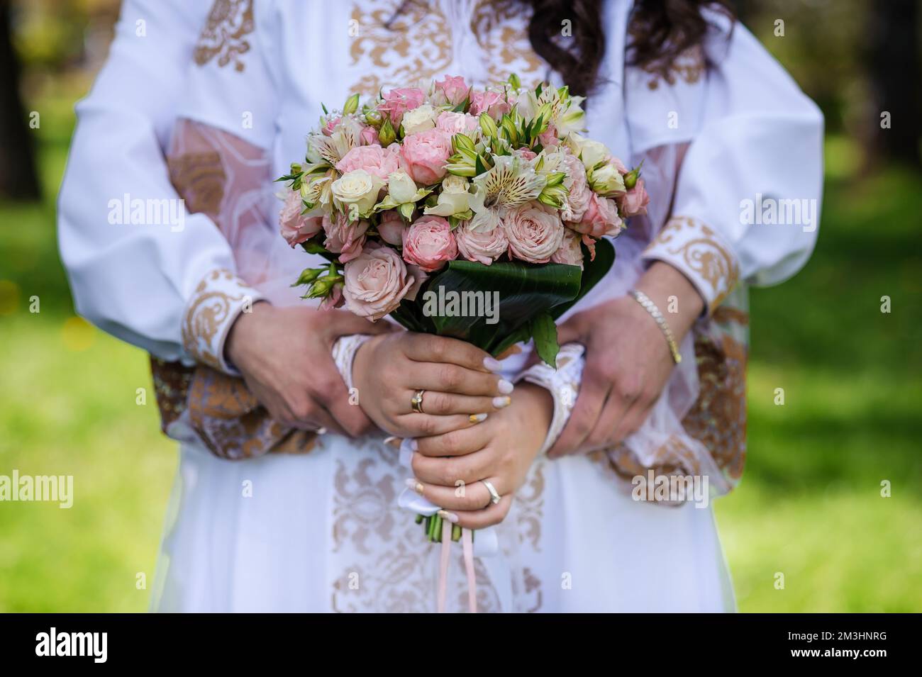 The groom holds the bride's hand, in the background a wedding bouquet ...