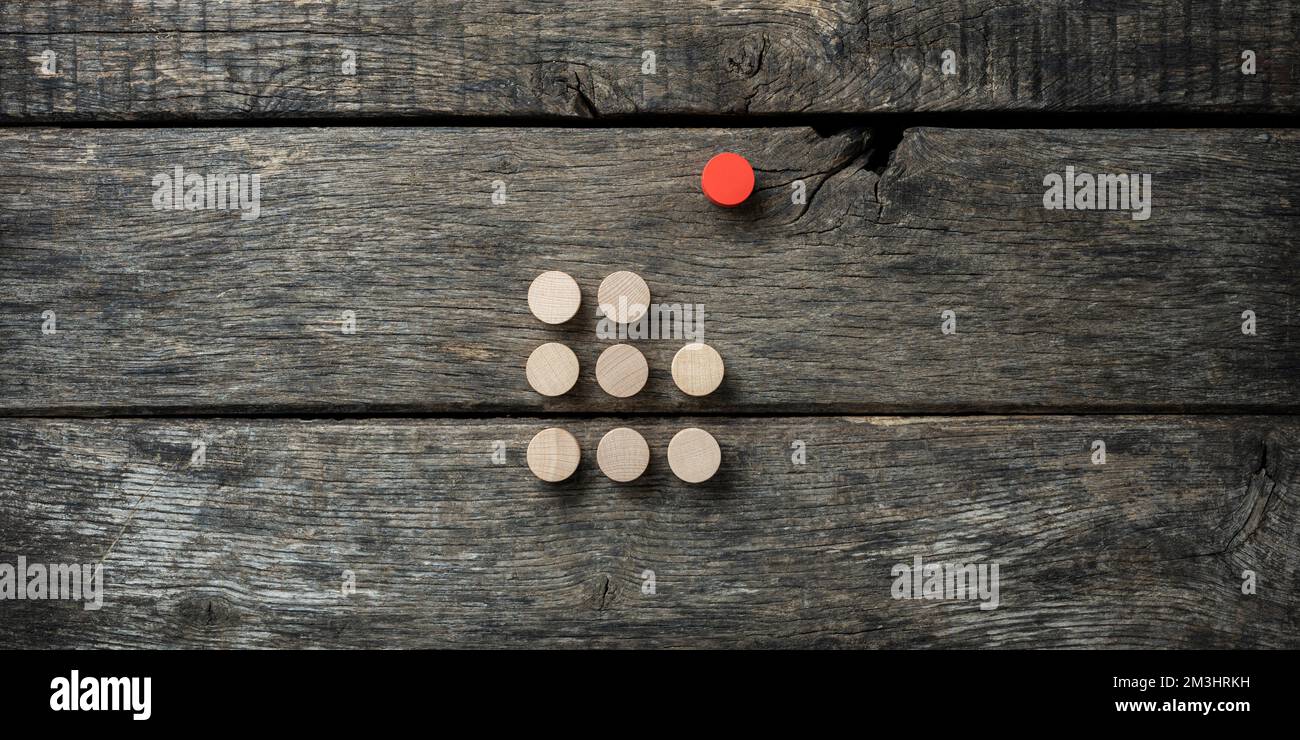Red wooden cut circle placed away from a group of plain round circles ...
