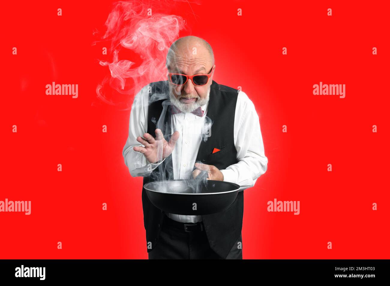 A man with a burnt frying pan in his hand. On a red background Stock ...
