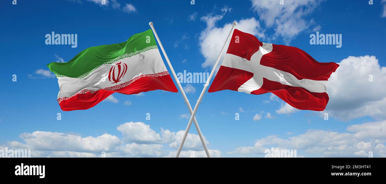 two crossed flags denmark and Iran waving in wind at cloudy sky ...
