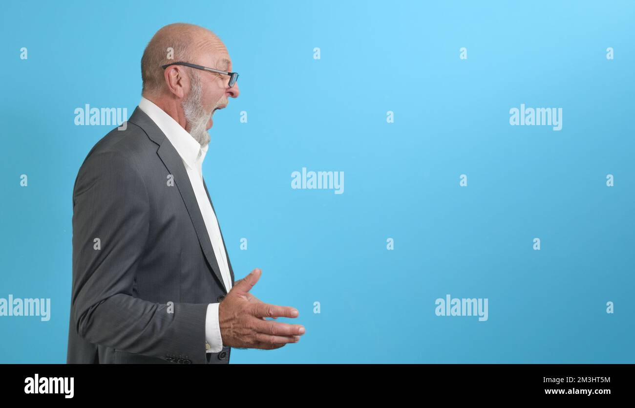 Emotional angry elderly man in profile on a blue background. copy space ...