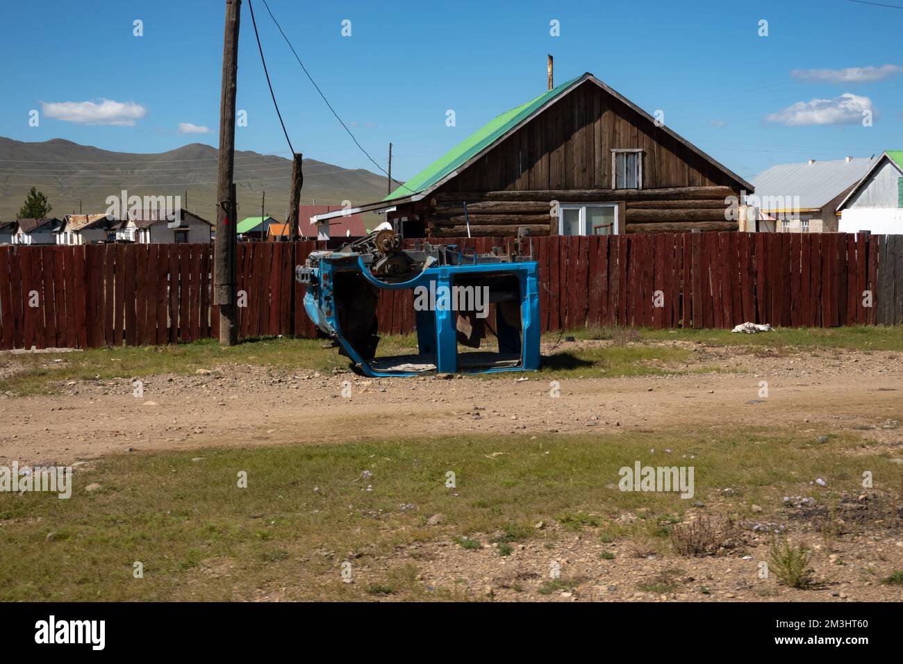 The frame of the abandoned car, fence and house in the background ...
