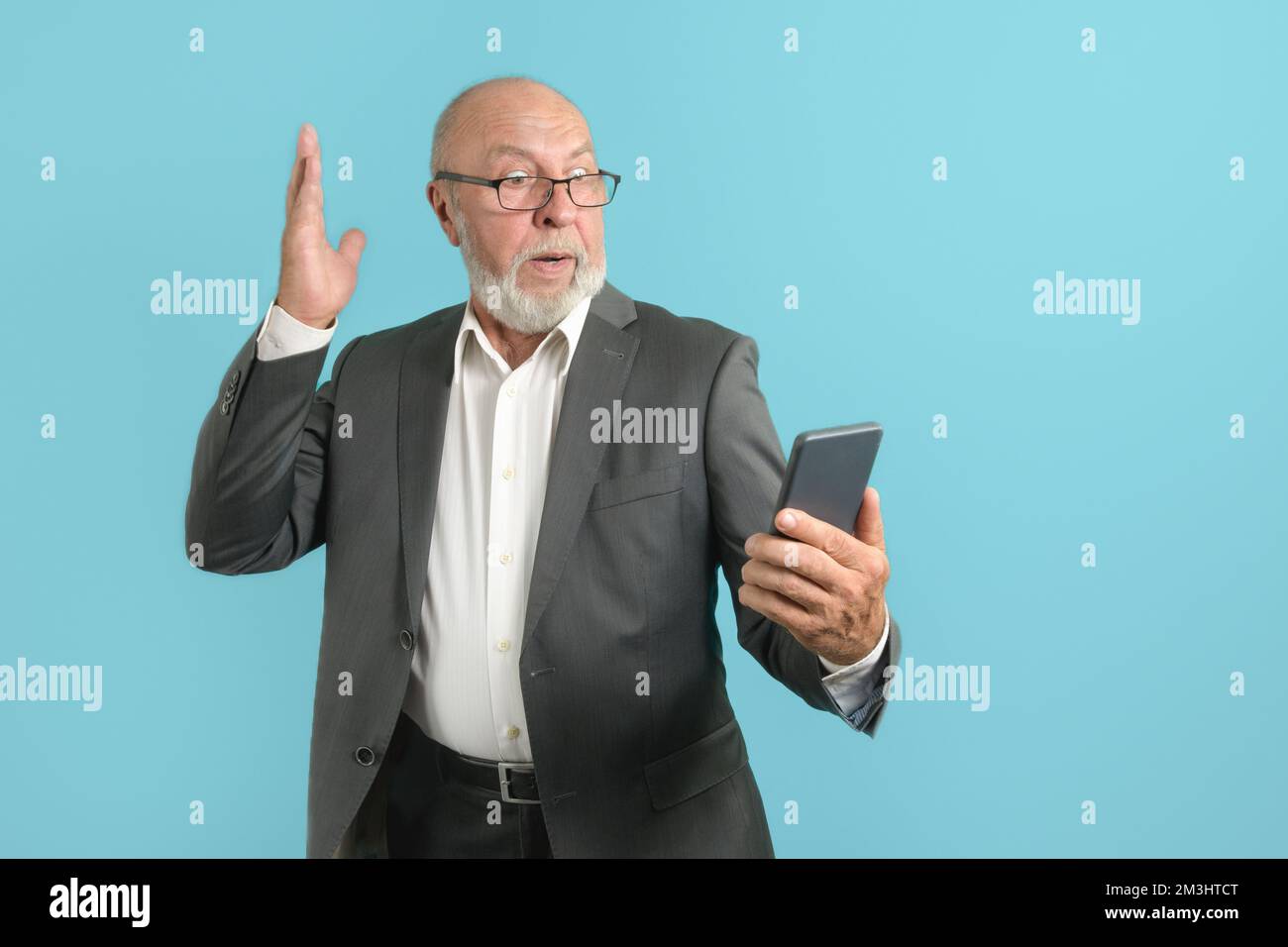 Surprised message. Handsome senior man in classic suit using mobile ...