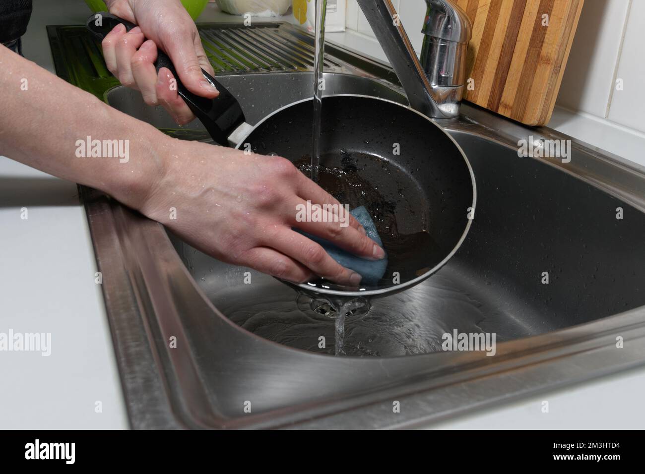washing the pan in the kitchen under running water Stock Photo - Alamy