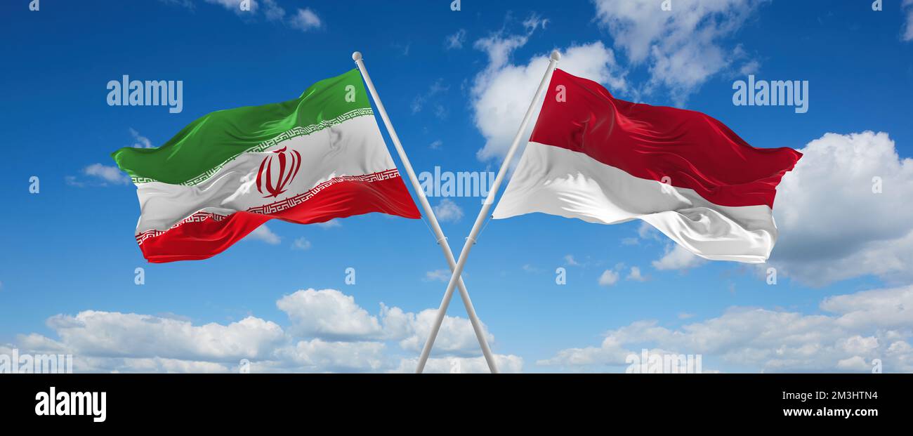 two crossed flags Indonesia and Iran waving in wind at cloudy sky ...