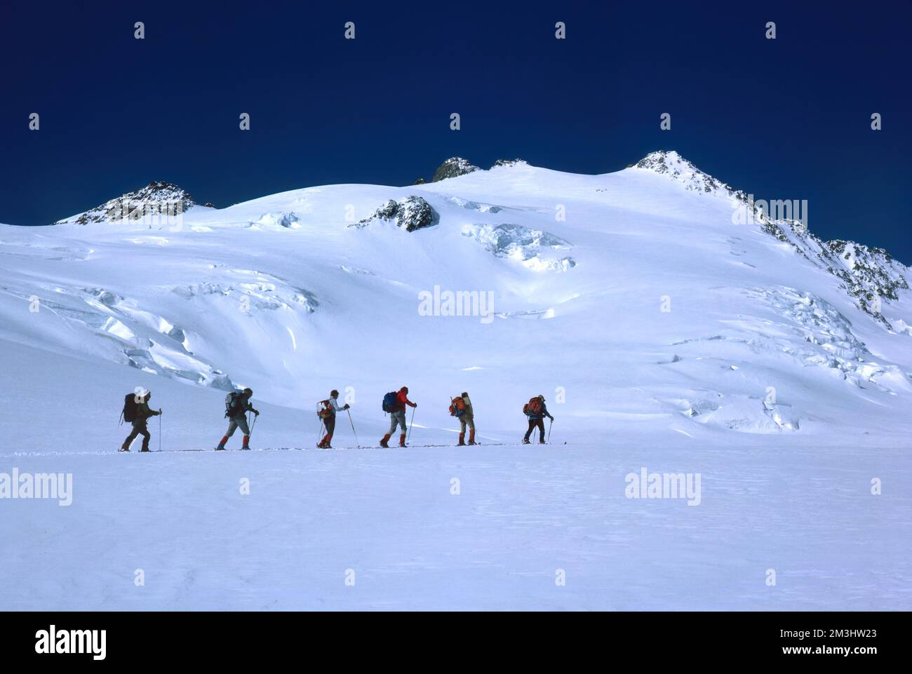 High alpine skiers on the way to the summit in winter Bernese Oberland ...