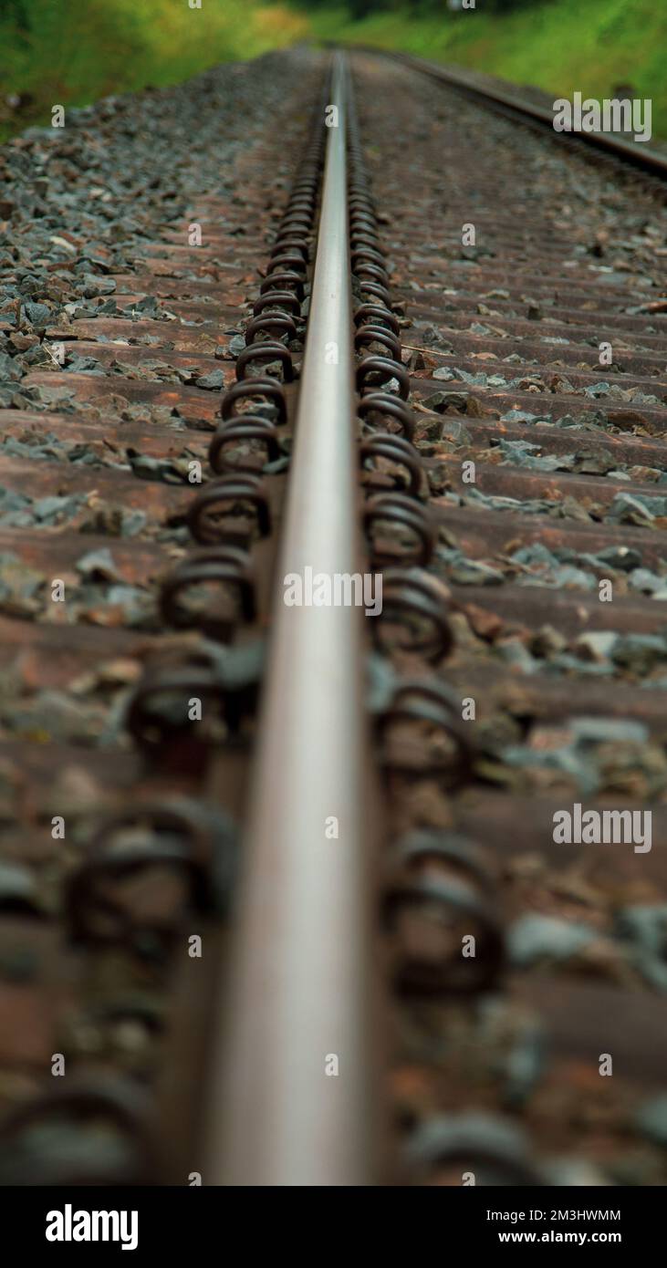 A vertical closeup of old rusty tram rails, grass background Stock ...