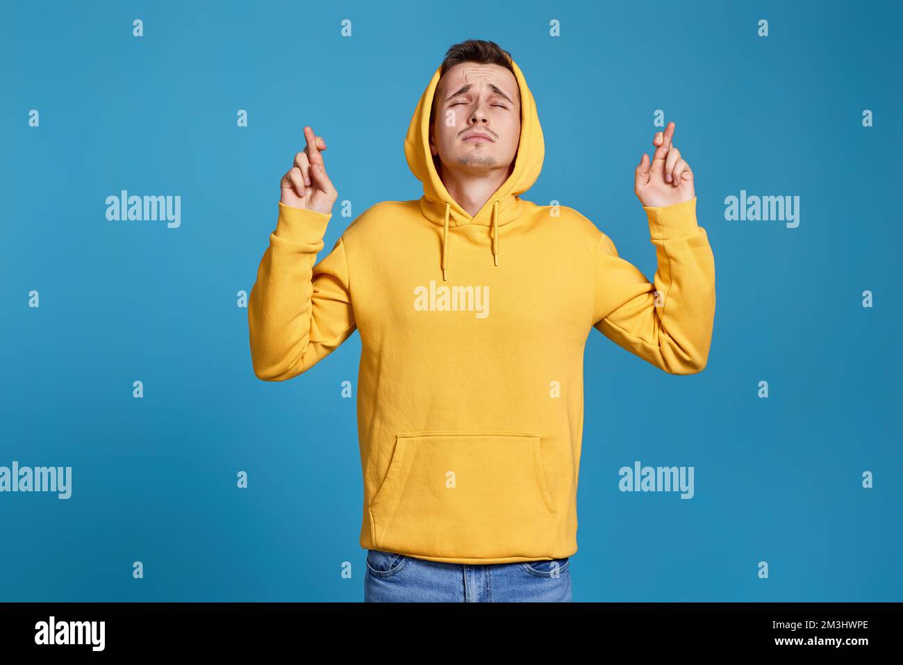 young man in yellow sweatshirt with finger crossed gesture Stock Photo ...