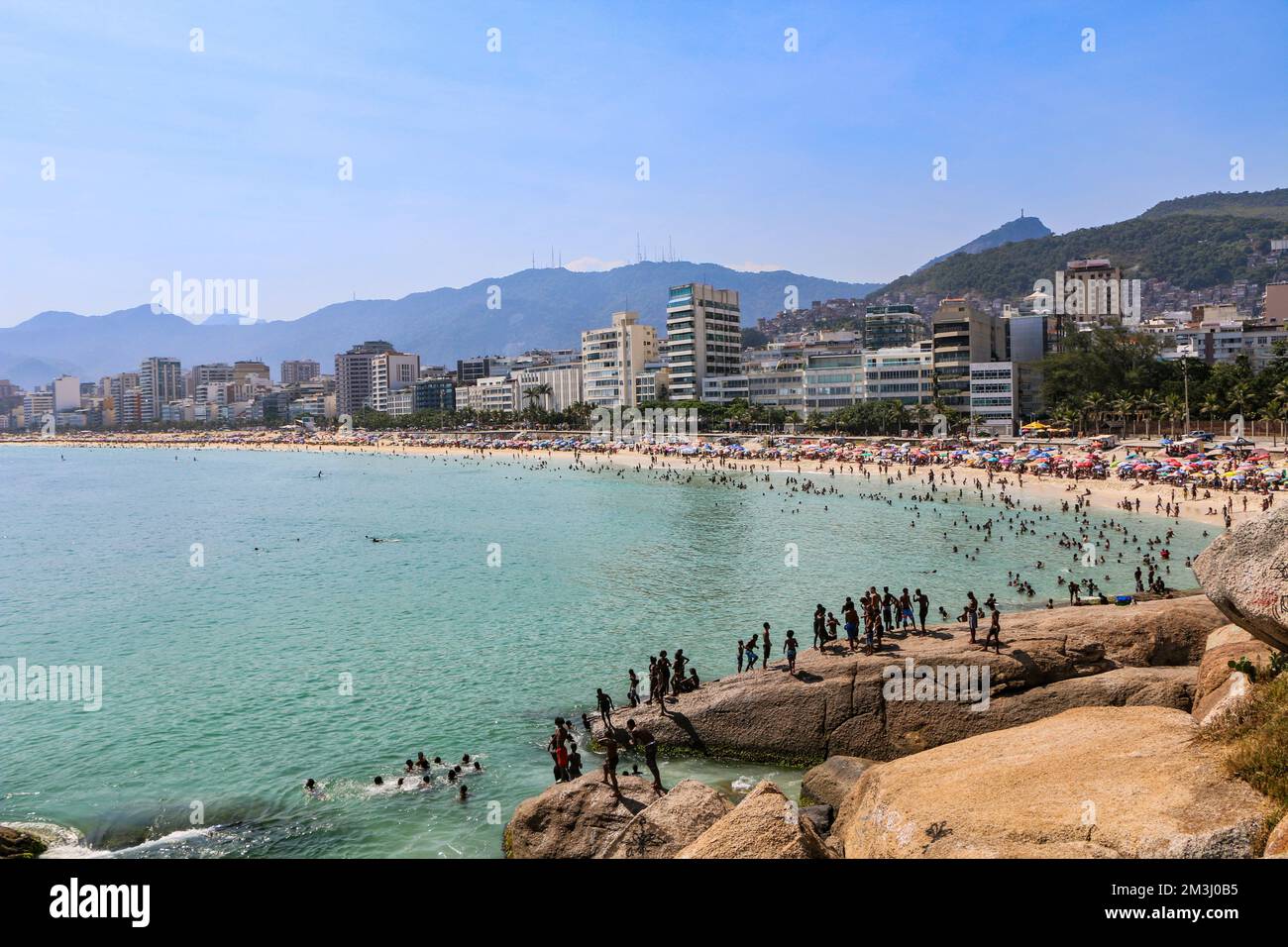 A beautiful view of crowded beach with huge rocks and buildings Stock ...