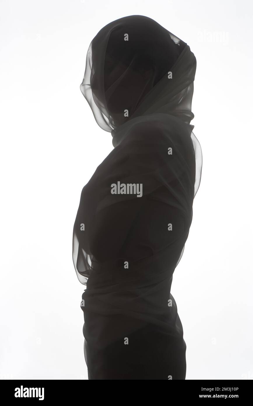 Silhouette of female body in profile fully wrapped in chiffon fabric on ...