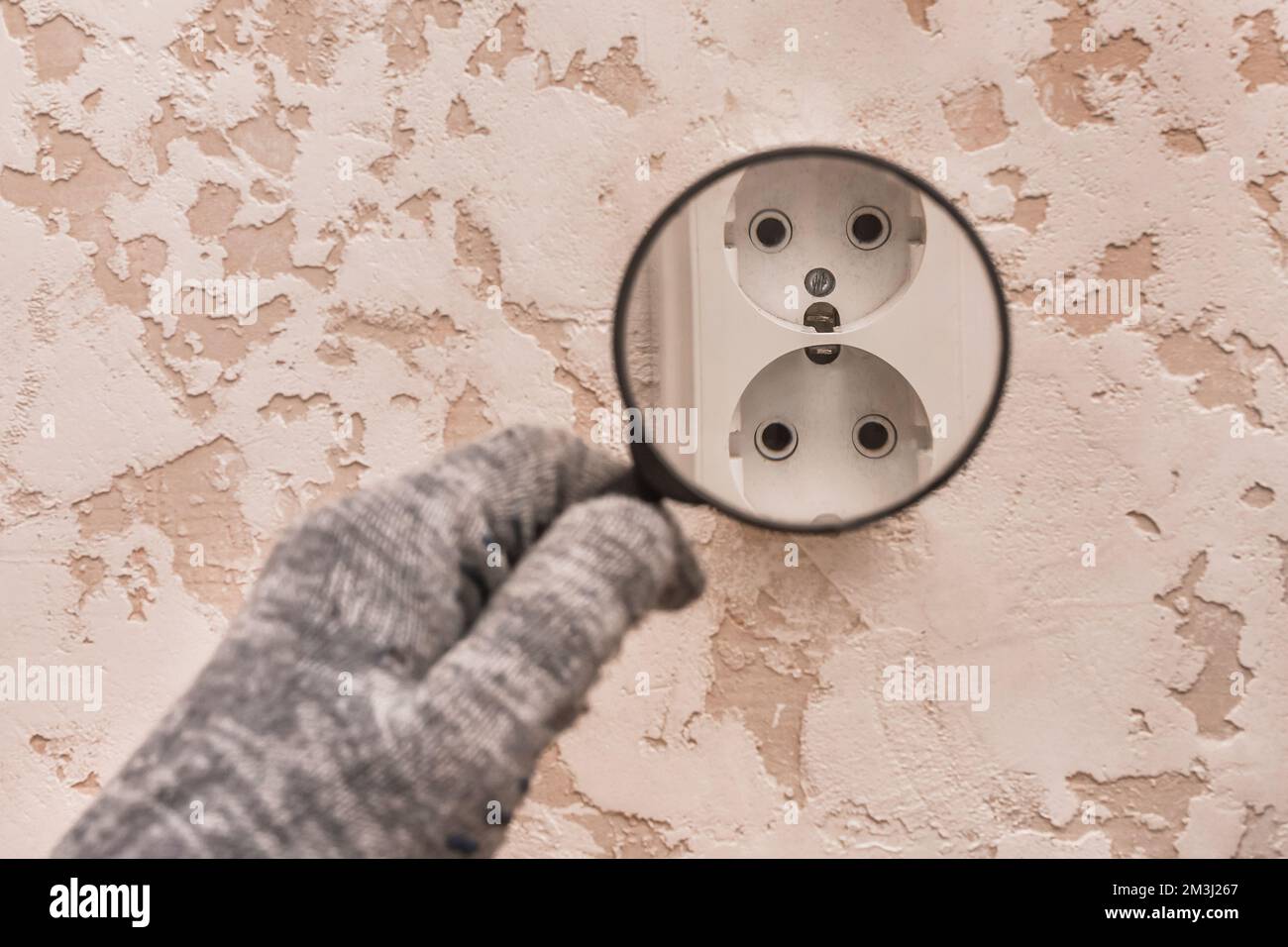 The hand of a construction worker in protective gloves examines through ...