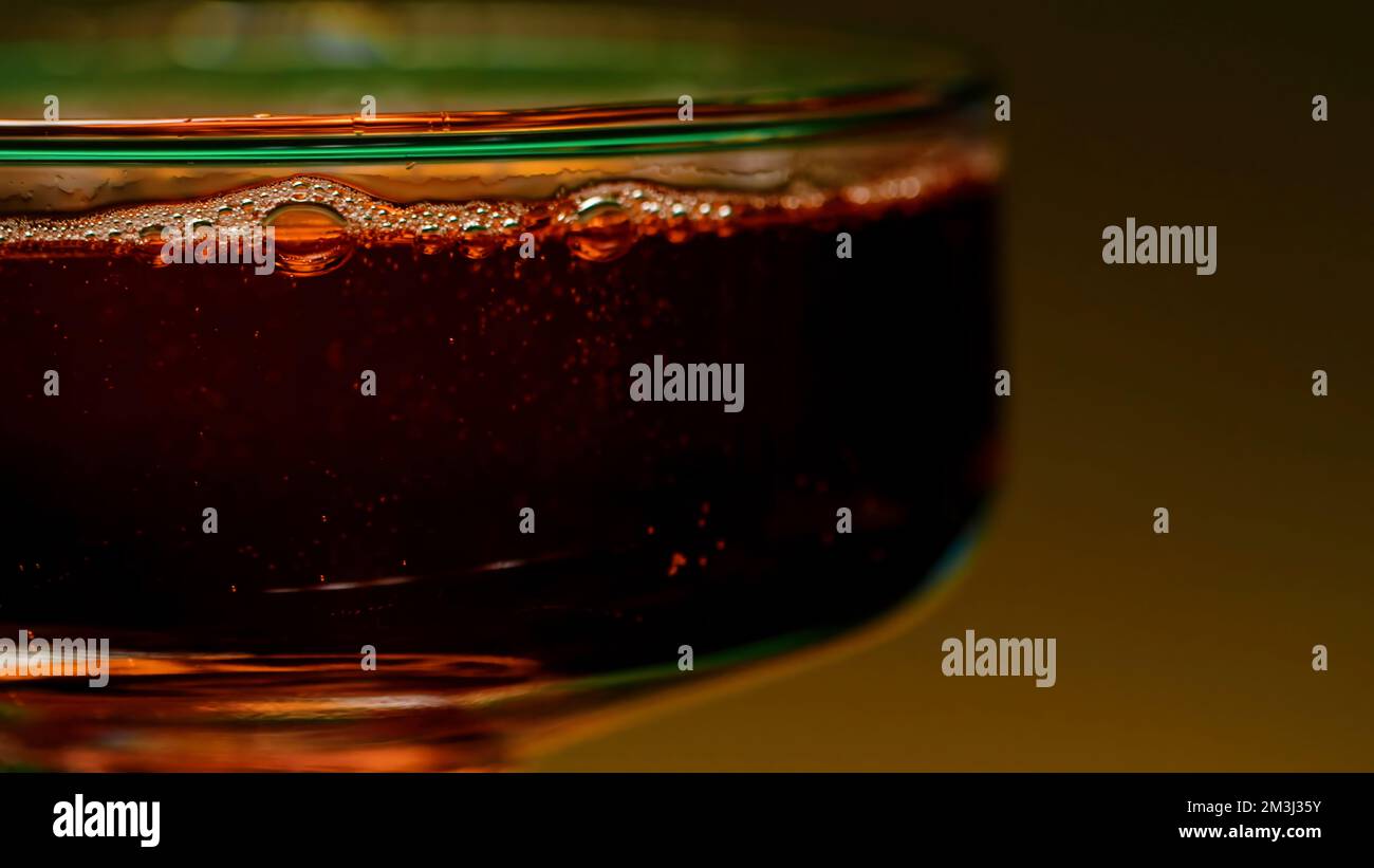 Close up of red soft drink inside a glass against a wall changing color ...
