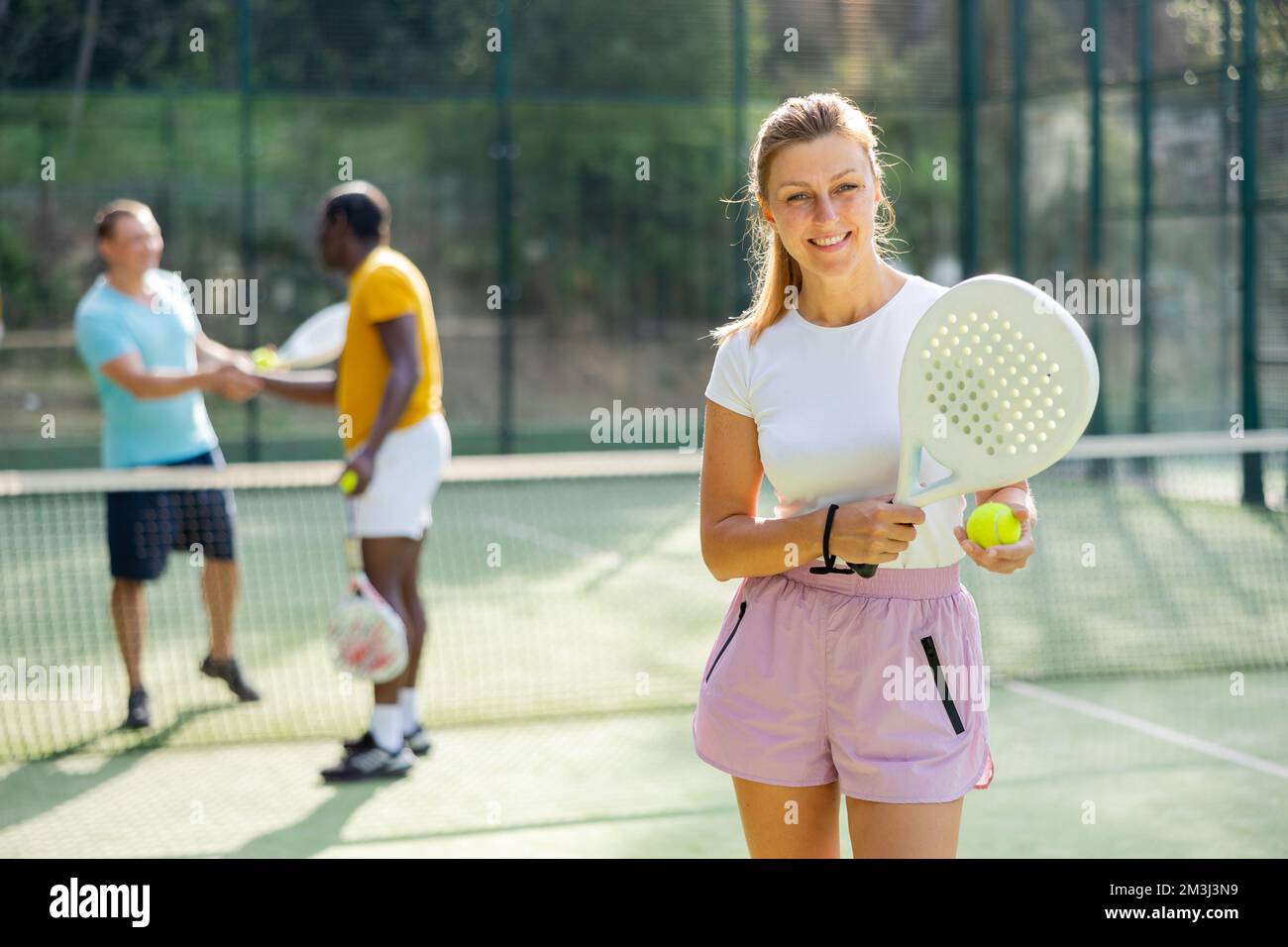 Woman posing with racket and ball in hands on padel court Stock Photo ...