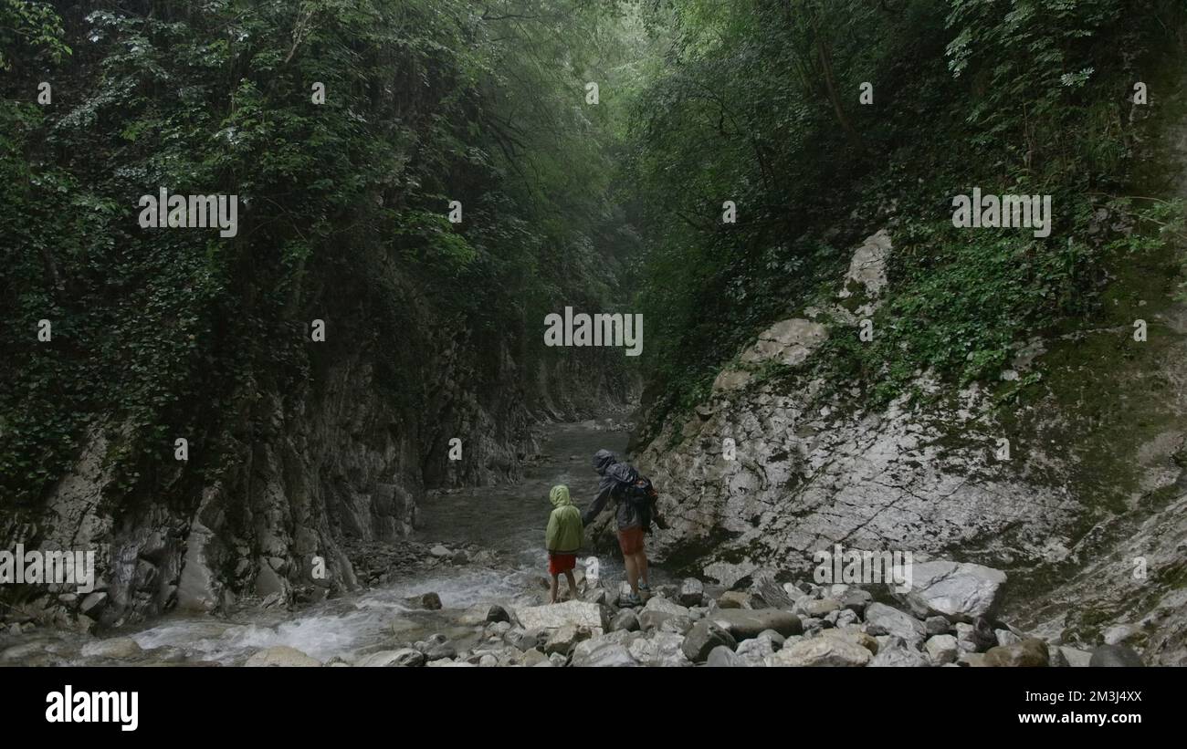 Tourists in forest gorge in rain. Creative. Wild river gorge in dark ...