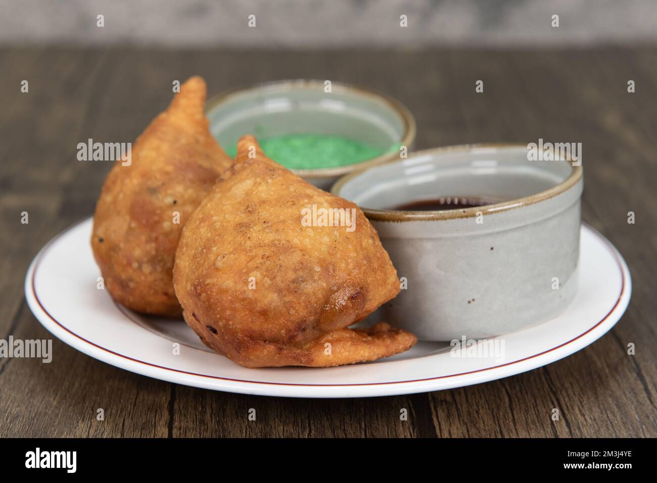 Crispy samosa pair on a plate with humus cipping sauce for an authentic ...