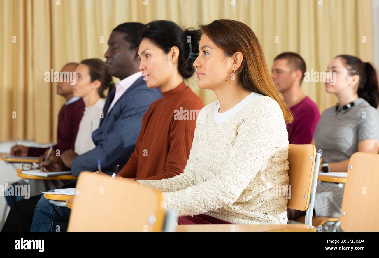 Multiethnic group of adult people studying together at tables in ...